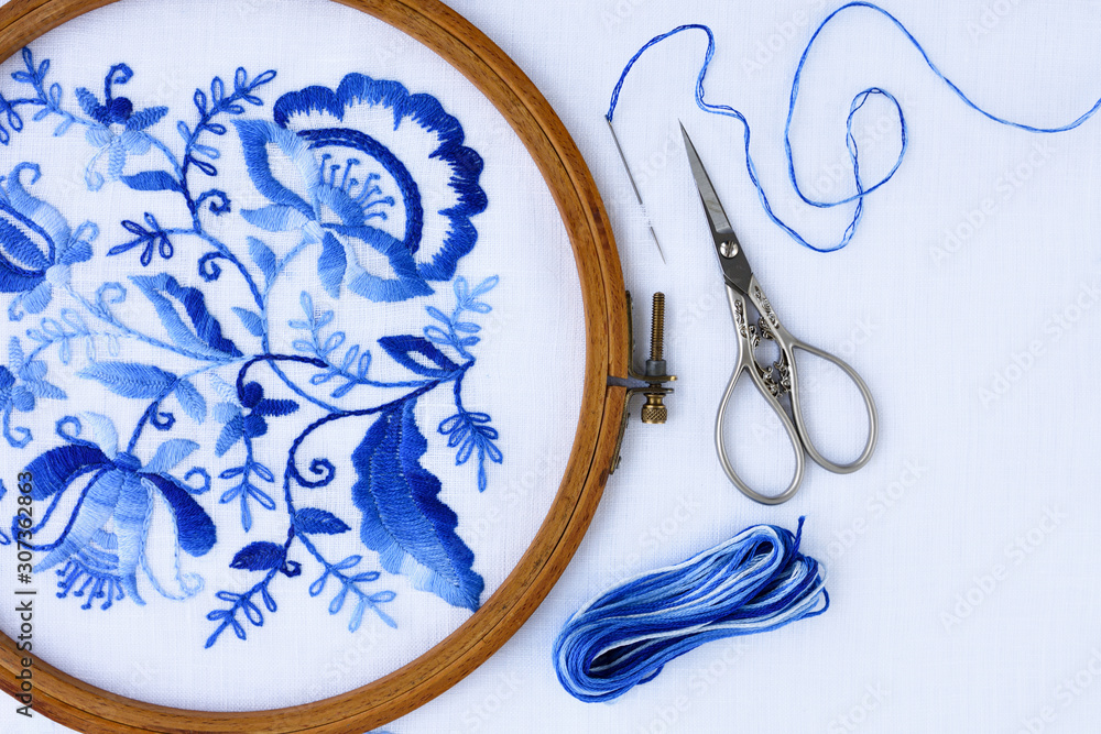 Embroidery hoop with fabric, sewing needle and thread, top view. Blue ...