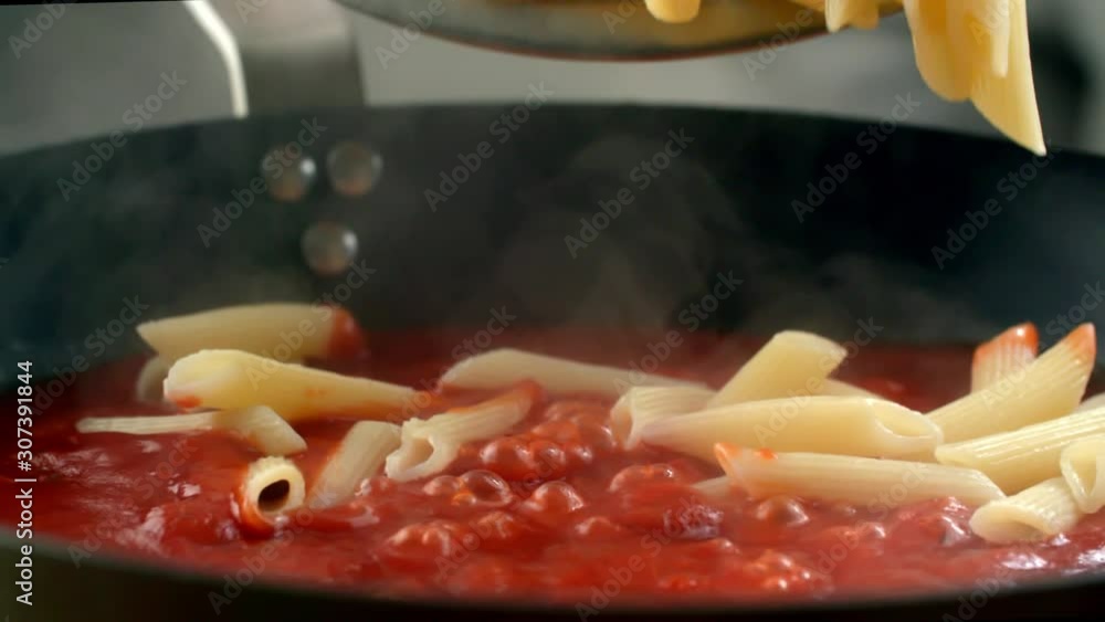 Penne pasta with hot tomato sauce boiled in a pan, cooking in slow ...