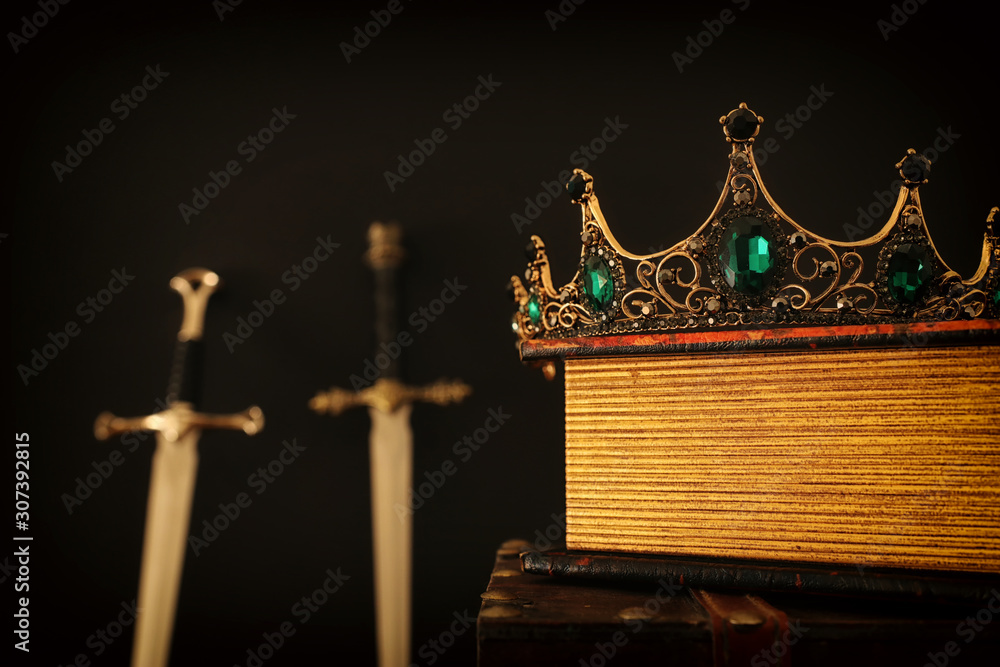 low key image of beautiful queen/king crown over antique book next to ...
