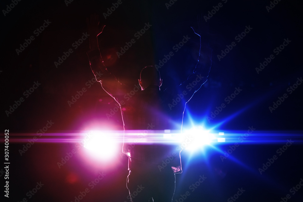 silhouette of a male criminal suspect with hands up during night ...