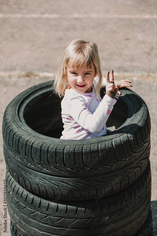 From above of happy adorable little girl standing in stack of car tires ...