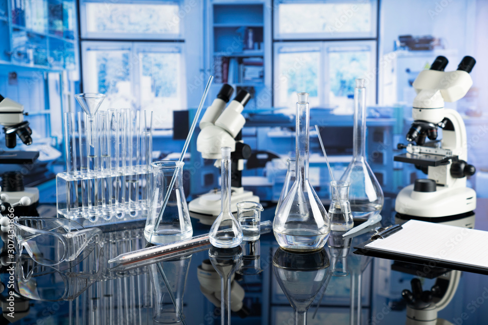 Science laboratory. Beakers, test-tubes and microscope on glass table ...