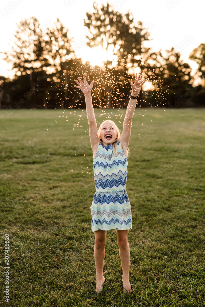 Happy tween girl throwing flowers in air at dusk Stock Photo | Adobe Stock