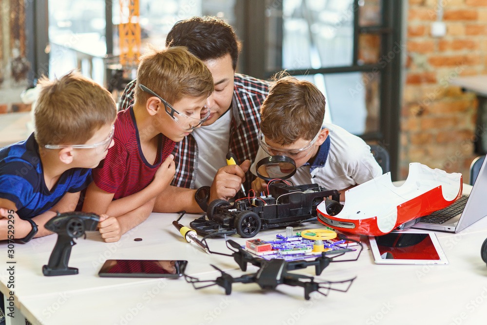 Electronic engineer with european school children working in modern ...