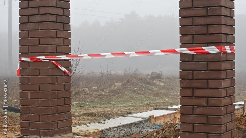Vidéo Stock Fence tape between two brick columns. Construction of ...