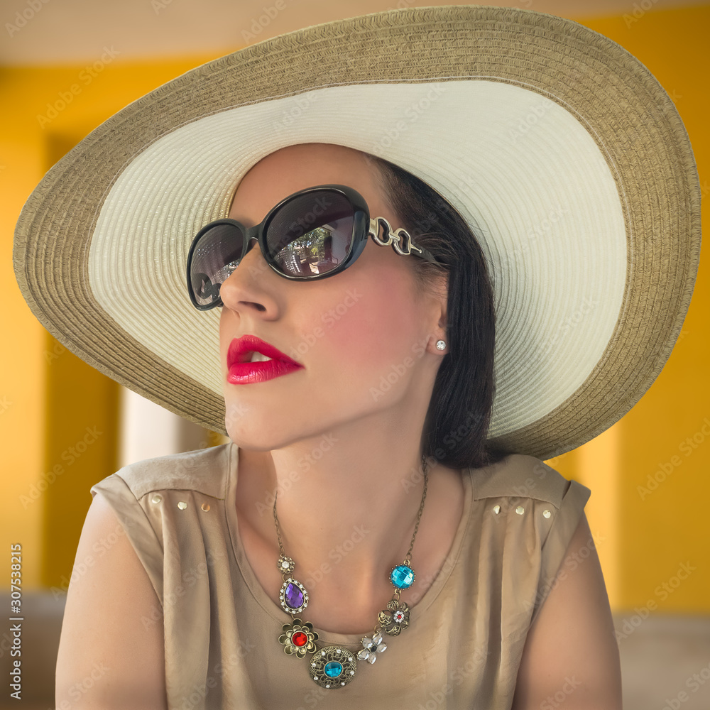 A glamorous socialite wearing a large rim straw hat and big sunglasses ...