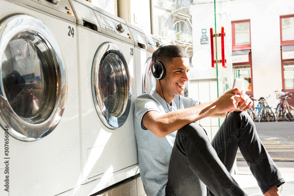 happy North African man sitting on floor leaning against wash machine ...