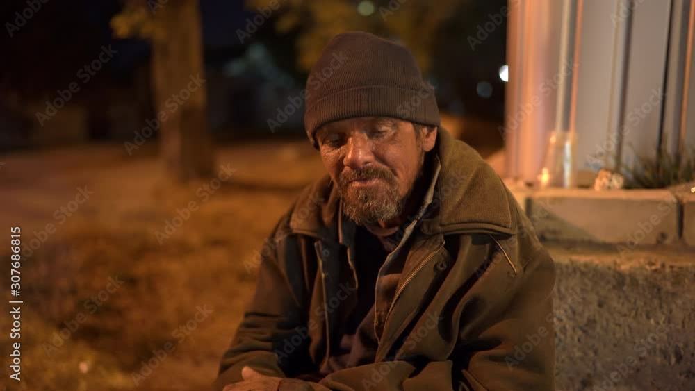 Sad homeless man sitting on the street at night. Stock Video | Adobe Stock