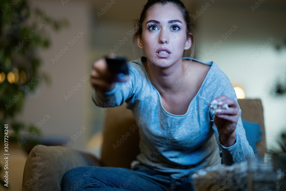 Shocked woman changing channels while watching TV at night. Stock Photo ...