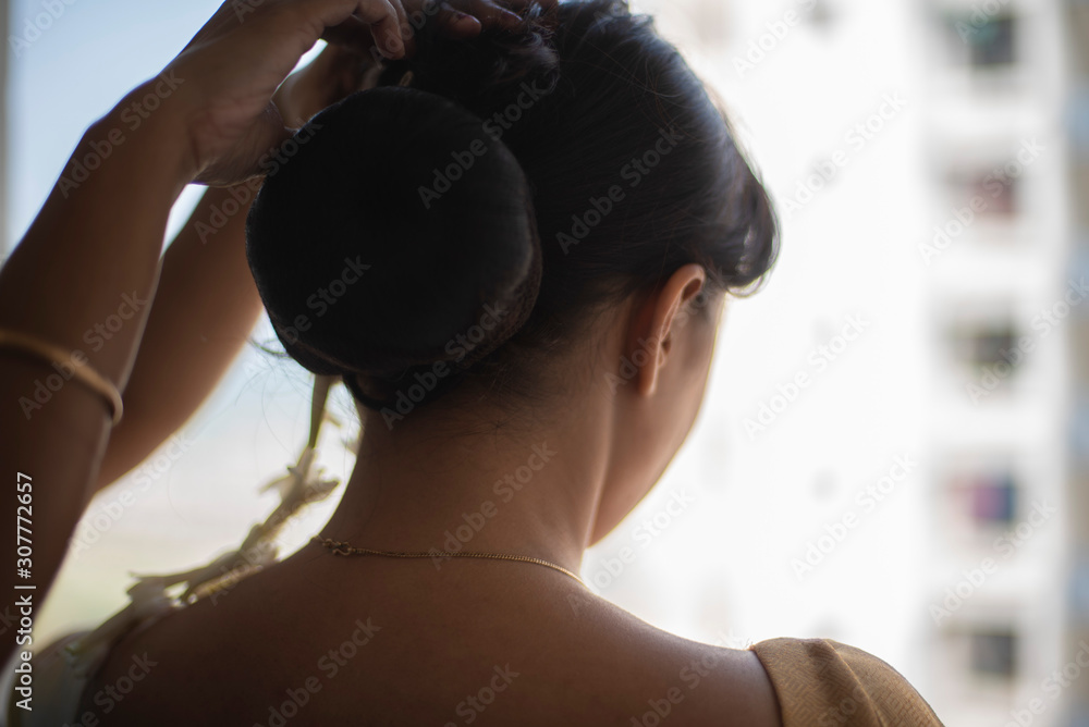 Backside portrait of an Indian woman in white traditional wear making ...