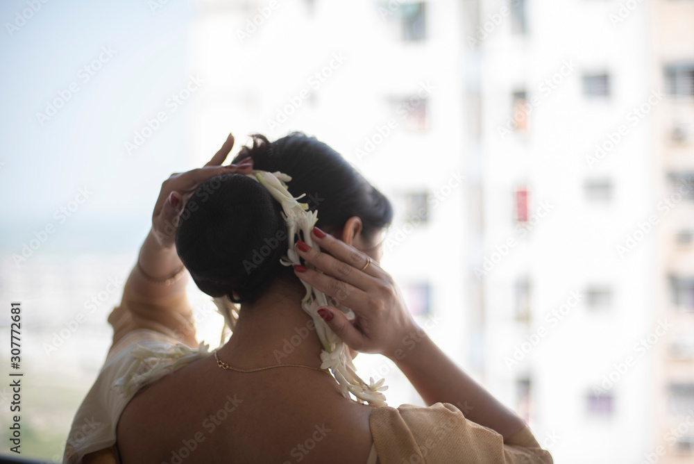 Backside portrait of an Indian woman in white traditional wear making ...