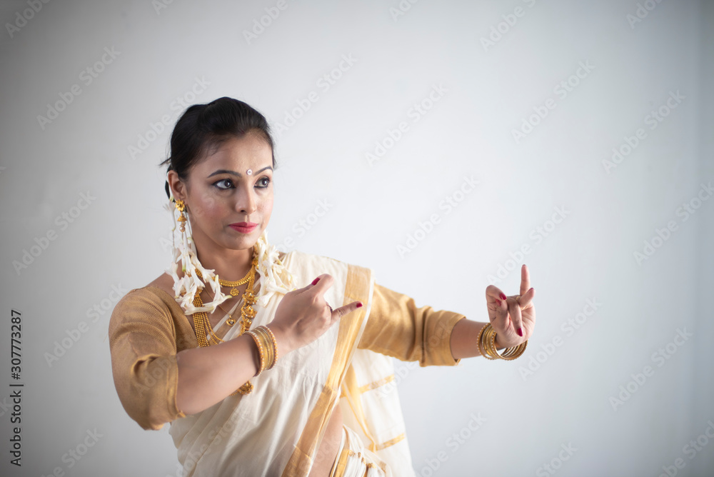 An young and attractive Indian woman in white traditional wear dancing ...