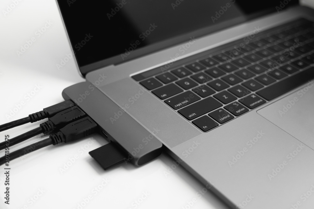 Laptop with USB Type-C adapter with pluged USB cables and SD card. The ...