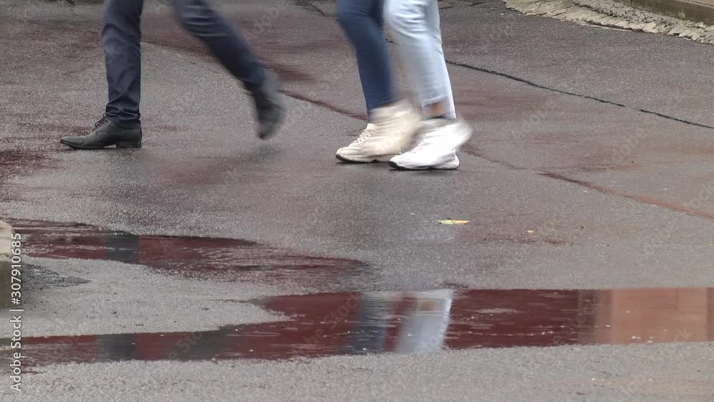 People walk in the rain. Fall. Wet feet. Youth in sneakers crosses the ...