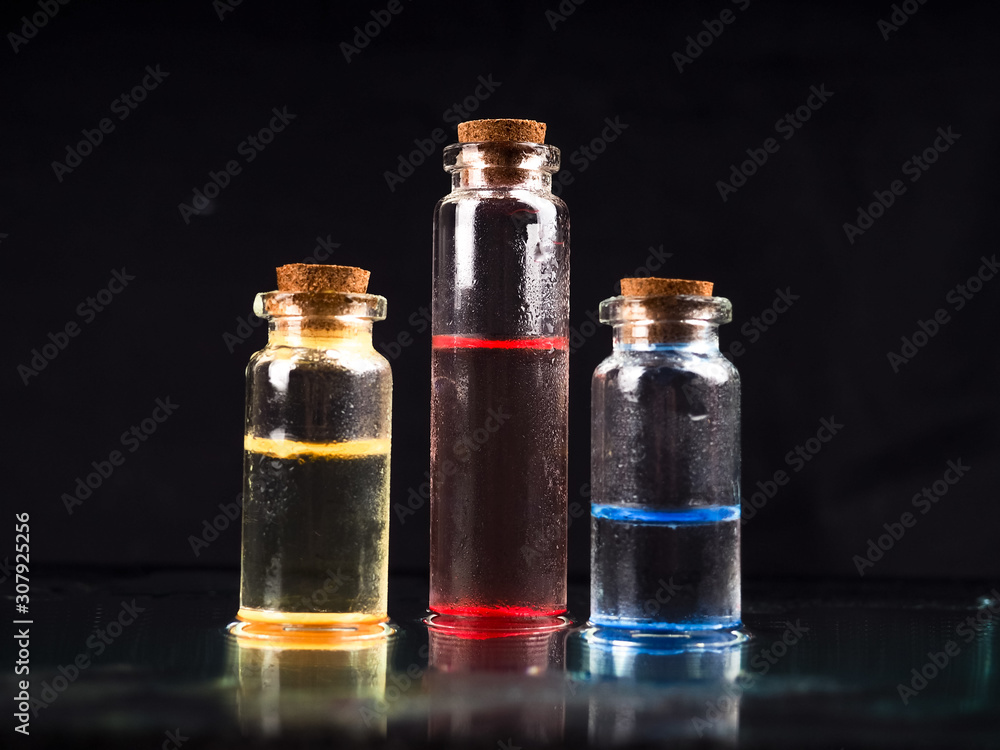 Three colourful liquid glass vial with black background for medical ...