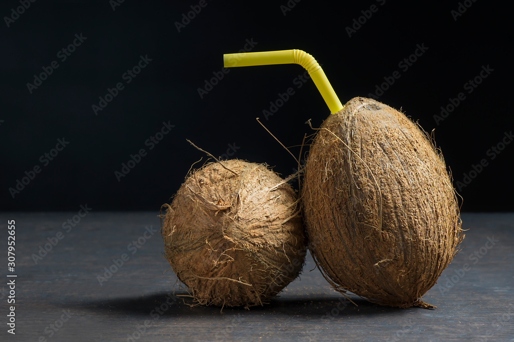 Organic natural whole coconut fruit with pipette or straw on rustic ...