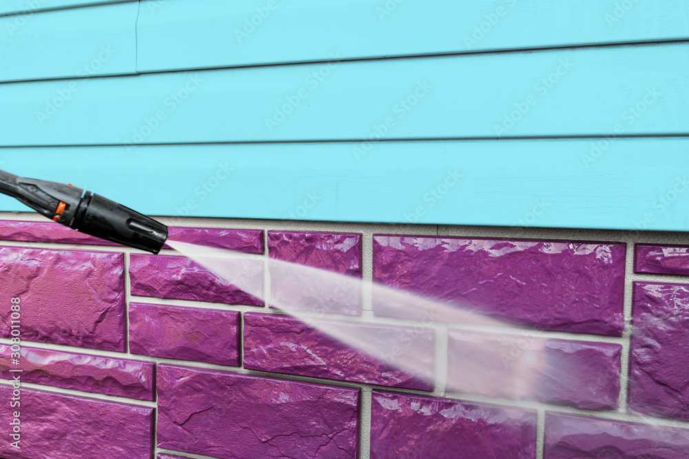 Foto Stock Cleaning service washing building facade with pressure water ...