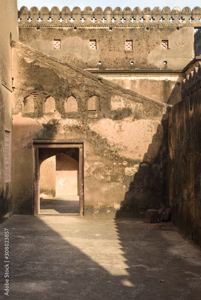 The geometric play of light and shadow inside the faded walls, arches ...