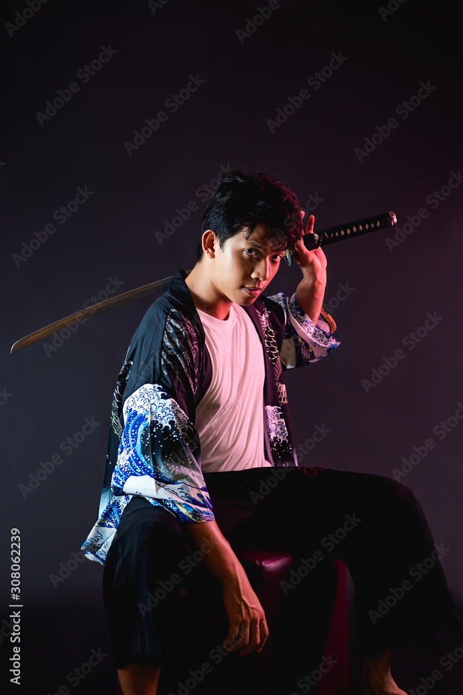 Asian man holding katana Japanese sword in his hand while sitting ...