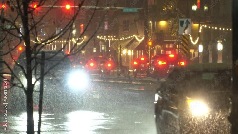 Traffic at intersection at night during wet snow storm as the light ...