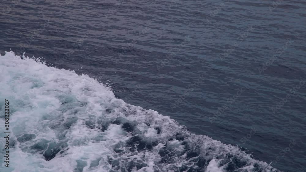 Close-up of waves forming behind a moving boat in Greece. In the shot ...