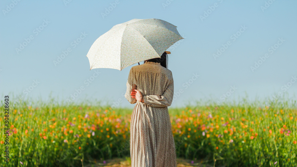 A young female tourist holds a parasol to see the vast and colorful ...