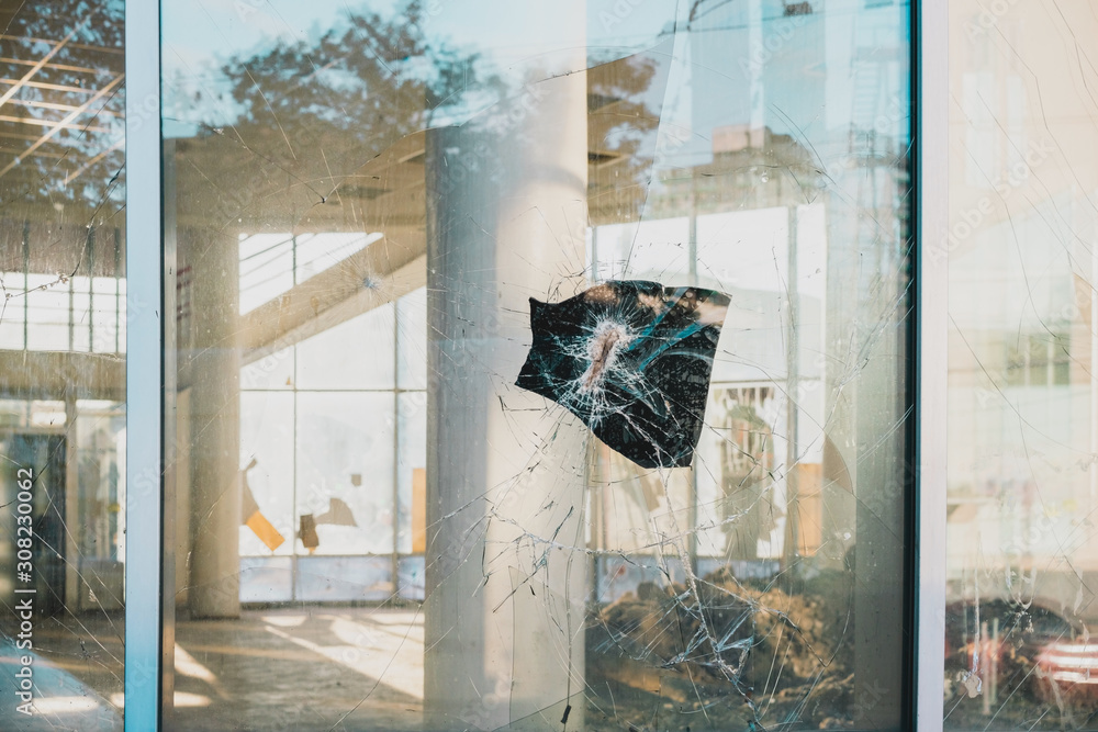 Broken and cracked glass window at the business center. Vandalism ...