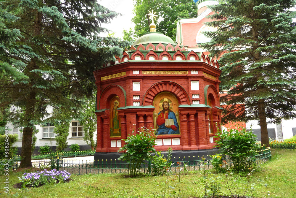The chapel is of red brick with gilded Orthodox icons. Green trees and ...