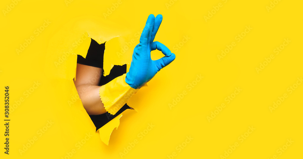 Hand in rubber blue-yellow glove shows OK gesture with fingers. Concept ...