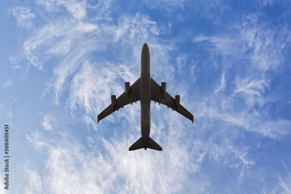 Bottom view of a plane with two turbines that flies against a blue sky ...