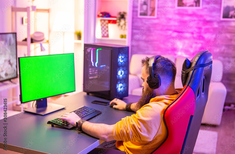 Man playing on powerfull gaming pc in a room with neon lights on a ...