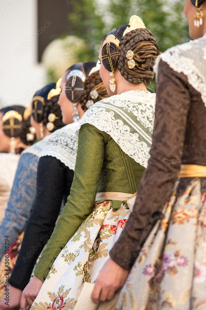 Falleras seen from behind. Dresses with floral designs and typical ...