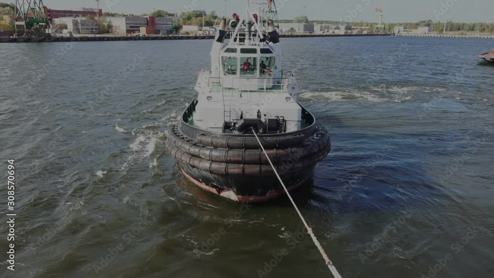 modern tugboat draws with rope oil tanker leaving tranquil harbor port ...