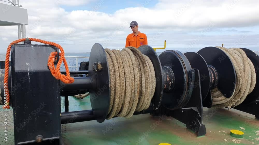 tanker sailor in orange uniform monitors mooring endship winding on big ...