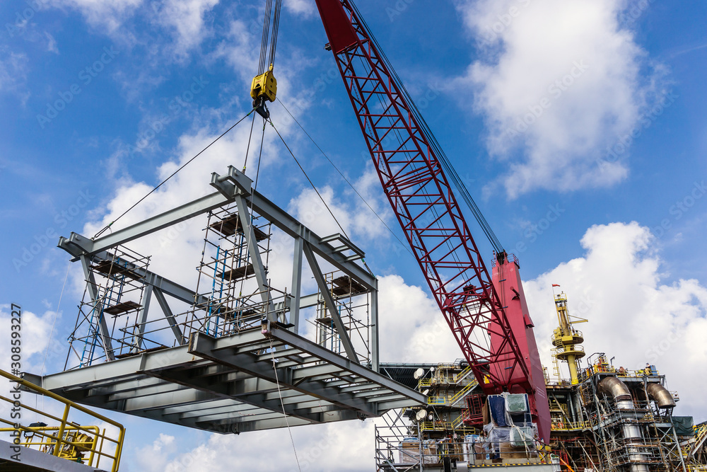 Offshore crane on board a construction work barge performing heavy ...