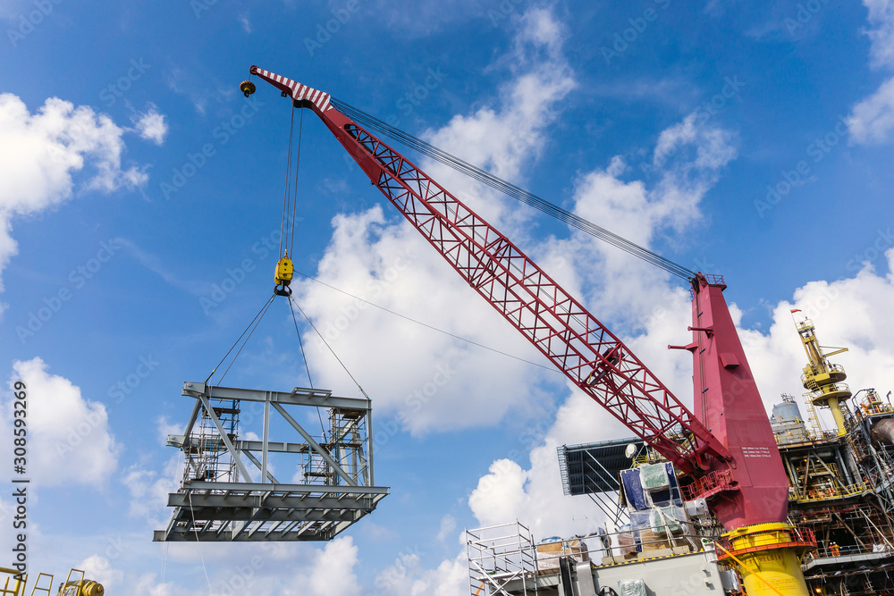 Offshore crane on board a construction work barge performing heavy ...