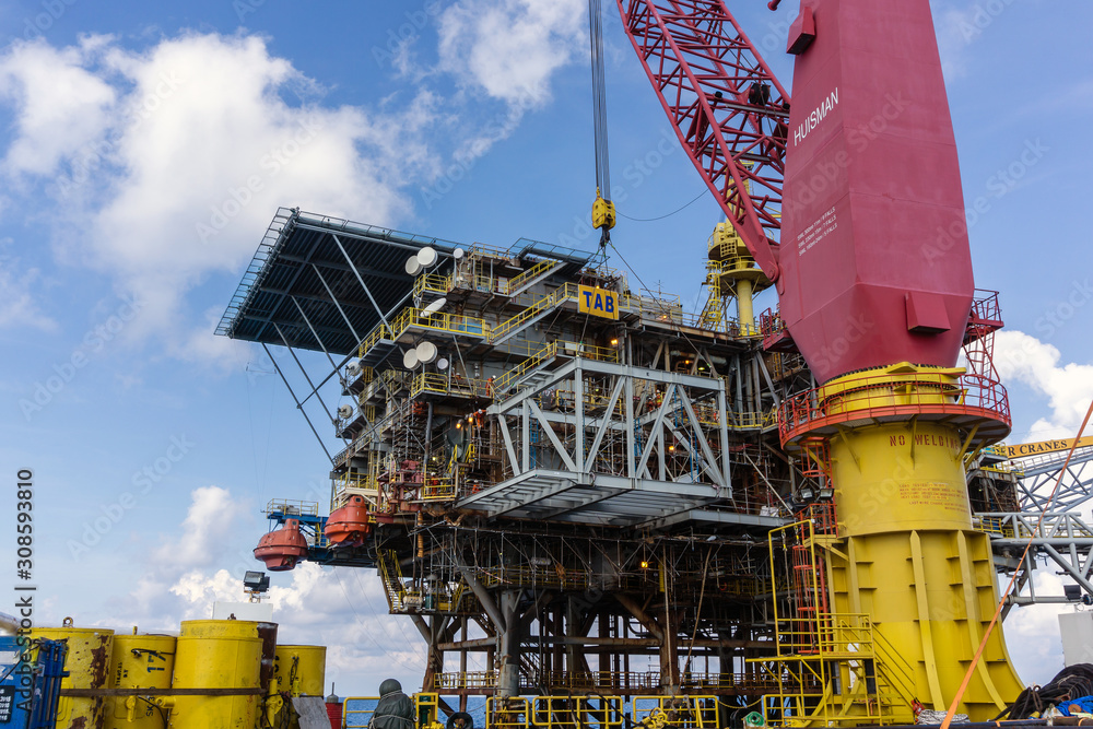 Offshore crane on board a construction work barge performing heavy ...