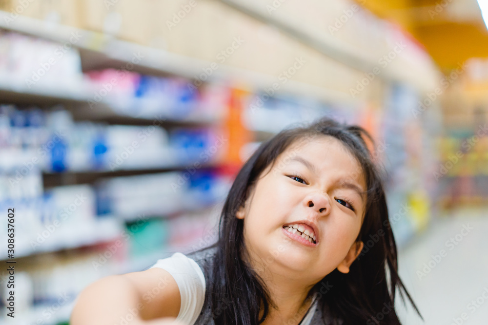 Angry little girl punch to camera in supermarket.Mad kid got upset and ...