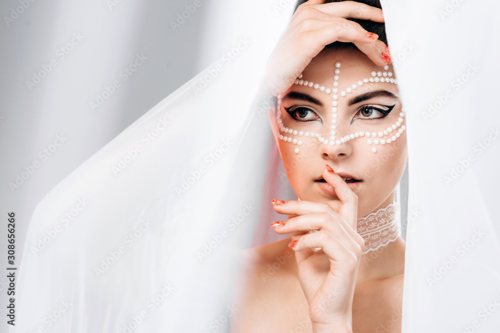 Fashion girl looks out from under the veil touches her face by her ...
