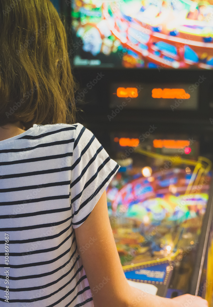 Little girl playing pinball game in theme park. foto de Stock | Adobe Stock