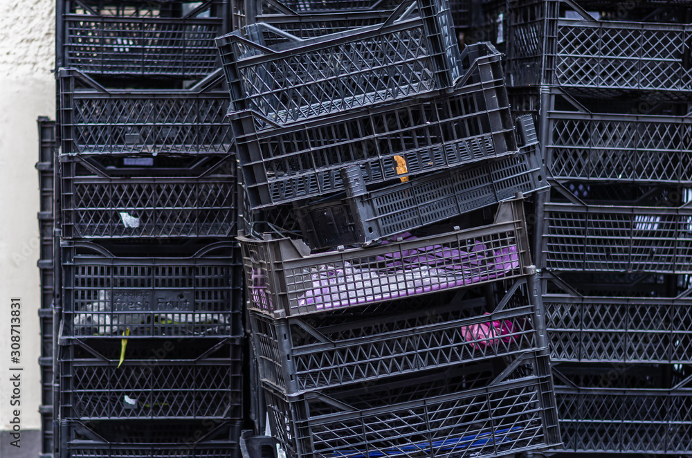 Piles of black plastic boxes for fruits and vegetables. Used boxes ...