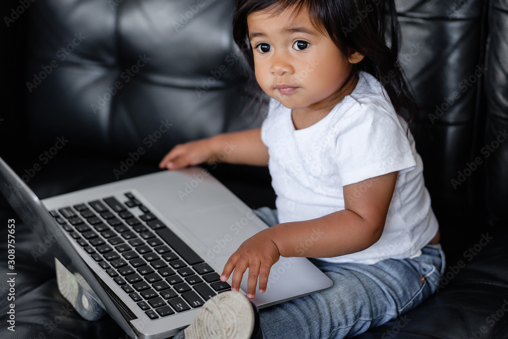 Side view of talented little mixed race girl pushing button on laptop ...