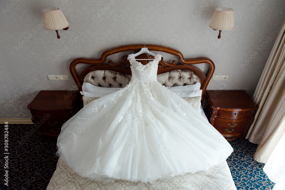Beautiful elegant white and lush wedding dress lying on the bed in the ...