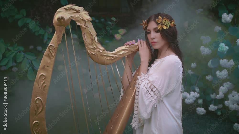 Mysterious brunette girl with love hugs touches elven old harp. Greek ...