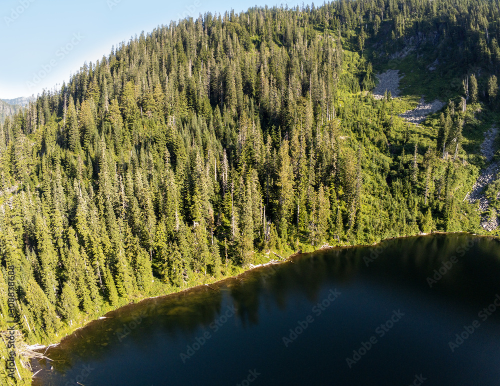 Secluded Kelcema Lake and the surrounding mountain and trees reflecting ...