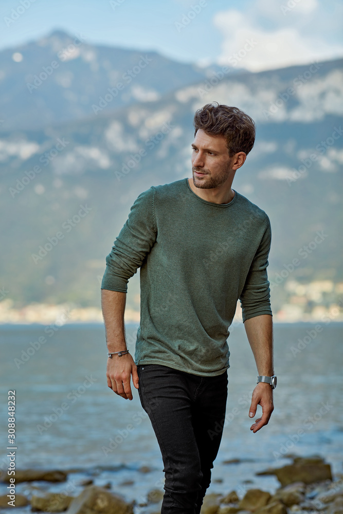 Handsome man walking on the beach over mountains background Stock Photo ...