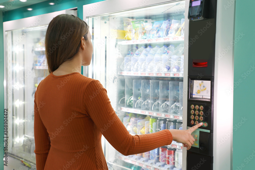 Young traveler woman choosing a snack or drink at vending machine in ...