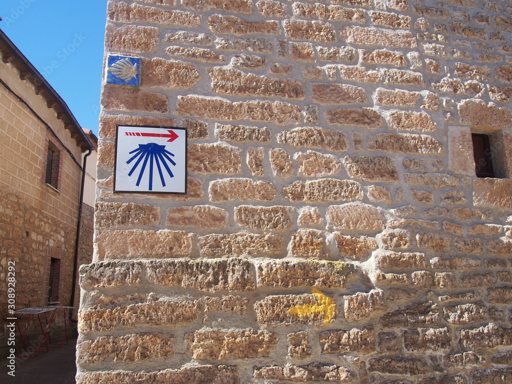 Scallop shell mark and yellow arrow sign on the wall, Camino de ...