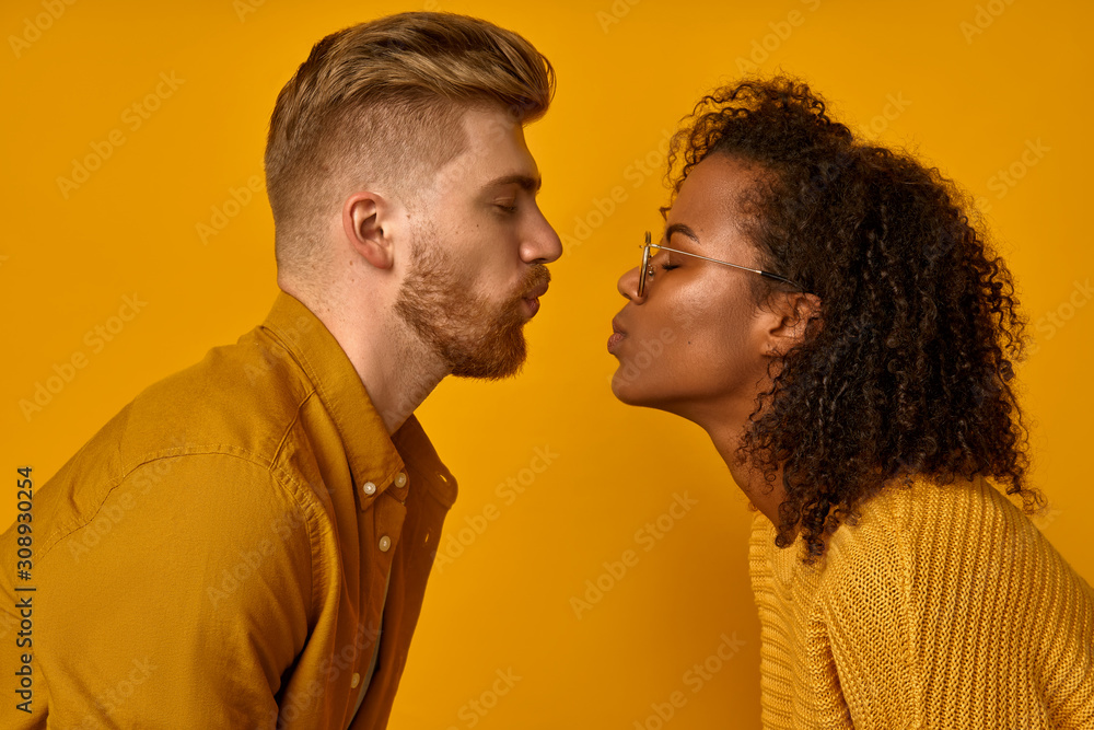 Mixed race couple stand in profile, keep lips folded, staring at each ...