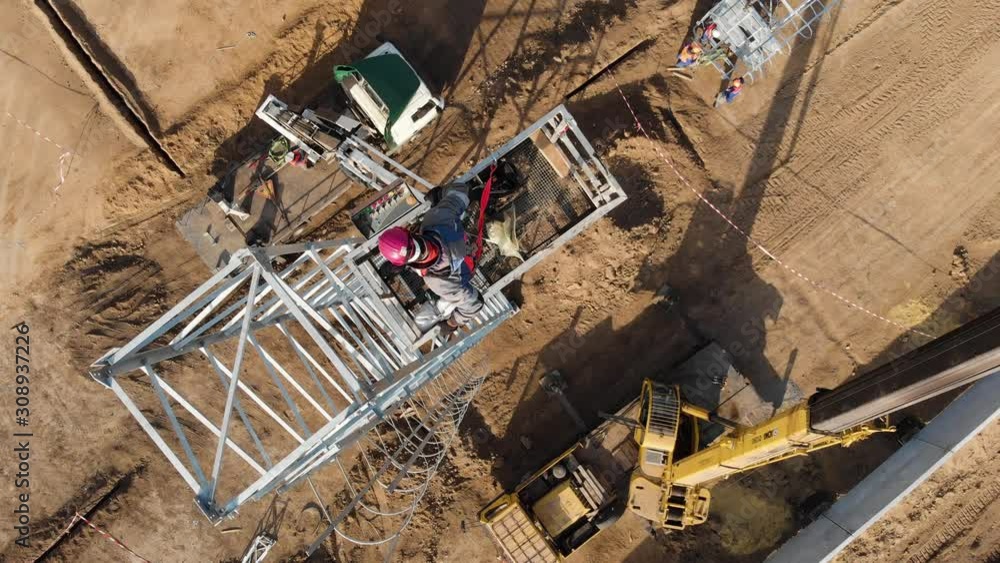 An installer at a height in the hydraulic elevator basket instructs the ...